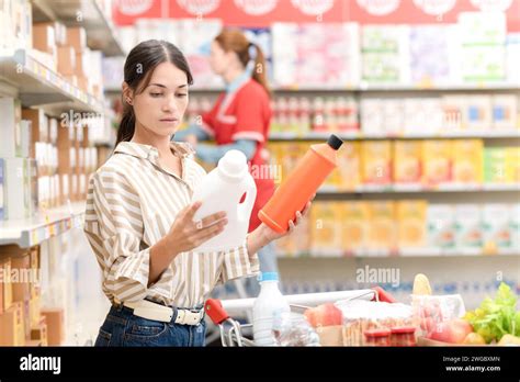 Customer Holding Two Bottles Of Detergent And Checking Labels She Is