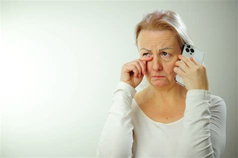 여자가 화가 나서 울고 눈물을 닦아 전화에 말한다 흰색 배경 전화와 재킷 사람들 헬프 라인 및 가정 폭력 개념 불행한 여자의 클로즈업 울고 스마트 폰으로 전화하는 걱정하는에