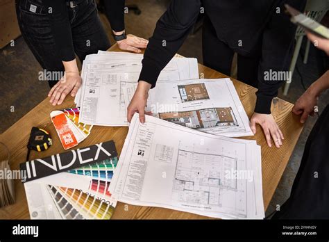 Team Of Architects Reviewing Blueprints And Discussing Project Details At A Desk Emphasizing
