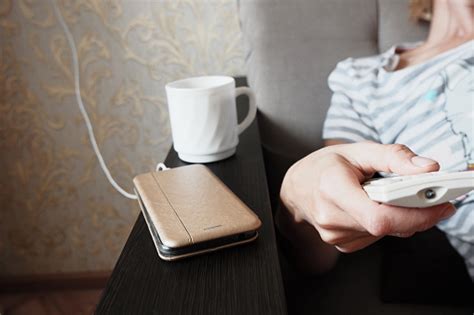 한 여성이 리모컨으로 Tv 채널을 전환합니다 인근에 전신전화가 전신선을 통해 충전됩니다 가정의 방에 대한 스톡 사진 및 기타