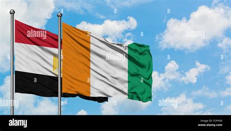 Egypt And Cote Divoire Flag Waving In The Wind Against White Cloudy