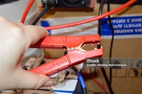 손으로 들고 빨간 점퍼 케이블 클램프 배터리 시스템 연결된 배선 설정 전문 전기 환경 에너지 저장 자동차 수리 독립형 전력