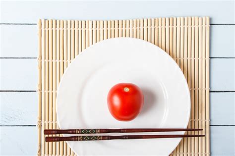 자연 유기농 토마토와 음식 흰색 접시에 막대기 대나무 매트 나무 테이블입니다 중국과 일본 부엌 개념입니다 상위 뷰 0명에 대한