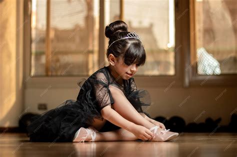 Premium Photo Little Ballerina Tie Ballet Shoes To Her Foot And Wear A Black Dress