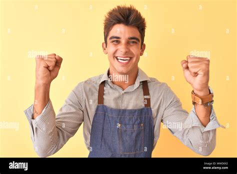 Young Handsome Employee Man Wearing Apron Standing Over Isolated Yellow