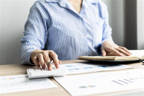 한 사업가가 흰색 계산기를 누르고 재무 부서 회의에서 메모한 노트북의 숫자를 살펴보고 보고서의 숫자의 정확성을 확인합니다 금융 컨셉 가격에 대한 스톡 사진 및 기타 이미지