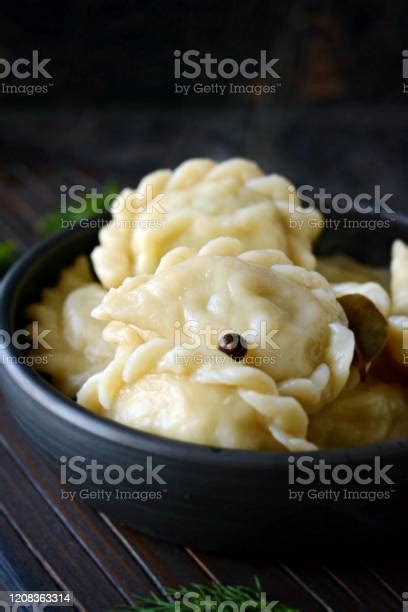 허브 향신료와 버터와 감자만두 어두운 배경에 세라믹 그릇 바레니키 바레니키 피에로기 피로히 만두를 채우는 Jiaozi에 대한