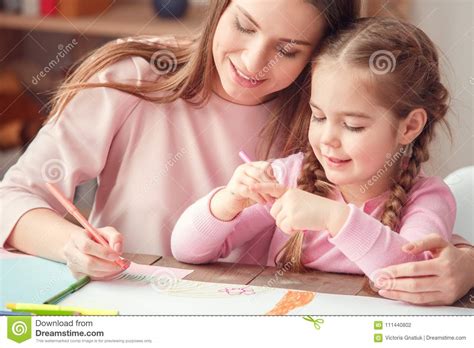 Mother And Daughter Weekend Together At Home Education Concept Sitting At The Table Hugging