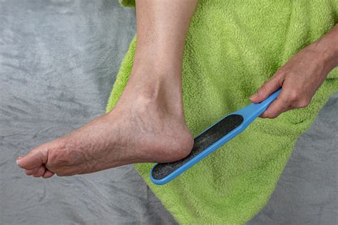 소녀는 발의 피부를 강판으로 발 뒤꿈치를 청소합니다 집에서 발 관리 여성 발의 발 뒤꿈치에 옥수수 제거 집에서 페디큐어 다리