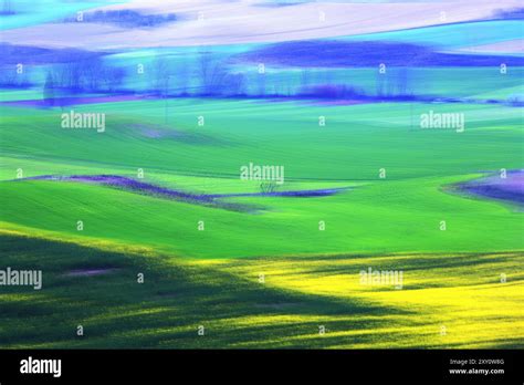 This Surreal Landscape Features Bright Rolling Fields Under A Dynamic