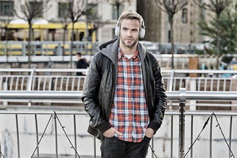 배낭 헤드폰을 가진 관광 힙스터 자기 향상 잘 생긴 남자는 음악 도시 배경을 즐길 수 있습니다 거리 교육 현대 교육 청소년을위한 팟 캐스트 온라인 교육 과정 음악 듣기