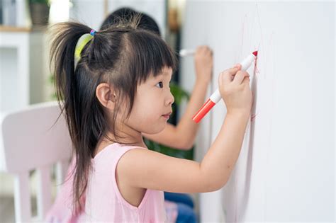 아시아의 젊은 형제 아이 소녀는 거실에서 흰색 벽에 페인트를 즐길 수 있습니다 재미있는 그림을 그리고 합창으로 예술 사진을