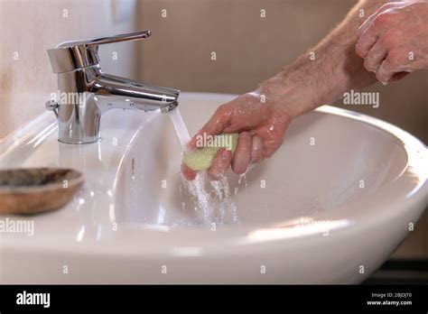 Hand Of Caucasian Man Holding Antibacterial Soap Under Running Water
