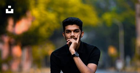 검은 크루넥 티셔츠와 검은 바지를 입은 남자가 회색 아스팔트 도로에 앉아 있다 사진 Unsplash의 무료 델리 사람들 이미지