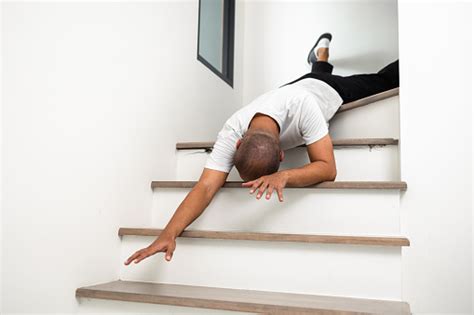 한 젊은이가 기절하여 집 계단에서 쓰러집니다 그는 사고로 부상을 입었고 계단에서 쓰러졌습니다 그는 아무도 도움을받지 못하는 집에서 혼자였습니다 부러진 뼈 계단에 대한 스톡
