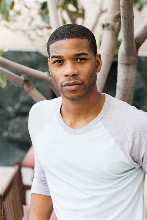 Black Guy Looking At Camera In Front Of Tree Branches By Stocksy