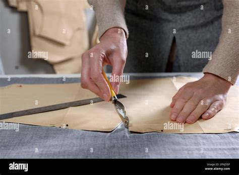 Tailor Transferring Sewing Pattern Onto Fabric With Tracing Wheel In
