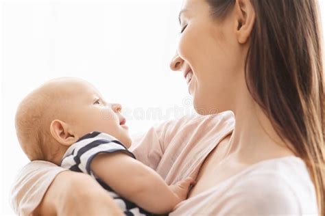 Madre Sosteniendo A Su Hijo Recién Nacido De Pie Cerca De La Ventana