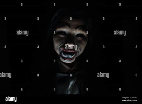 Scary Possessed Girl With A Creepy Doll Makeup In A Dark Room Horror Concept Stock Photo Alamy