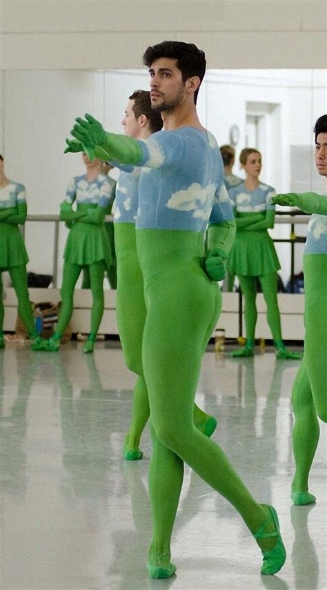 Two Men In Green And Blue Outfits Are Dancing With Their Hands Out To Each Other