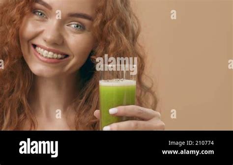A Cheerful Woman With Curly Hair Enjoys A Refreshing Green Juice