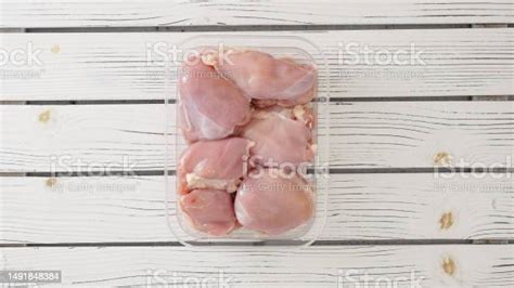 흰 나무 판자에 플라스틱 용기에 있는 원시 껍질 없는 뼈 없는 닭 허벅지 복사 공간 닭 넓적다리살 고기에 대한 스톡 사진 및