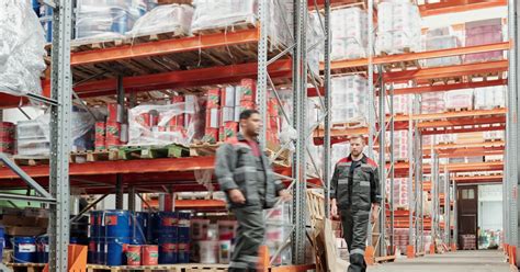 제복을 입은 두 명의 젊은 다문화 남성 노동자가 대형 공장이나 창고 안에 포장된 상품과 함께 거대한 선반을 따라 움직입니다 사진 Unsplash의 제조 이미지