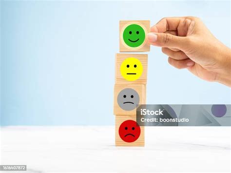 행복한 얼굴 아이콘이있는 나무 큐브를 손에 들고 있으면 서비스에 최고의 만족을 줄 수 있습니다 개념에 대한 스톡 사진 및 기타