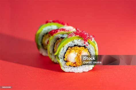 새우 아보카도 날아다니는 생선 캐비어가 붉은 색 배경에 있는 초밥 롤 세트 긴 그림자와 색상 배경에 창조적 인 이미지 빨강에