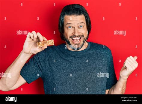Middle Age Caucasian Man Eating Protein Bar As Healthy Energy Snack