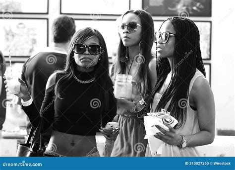 Three Women Standing In A Line Talking To One Another While Other Watch