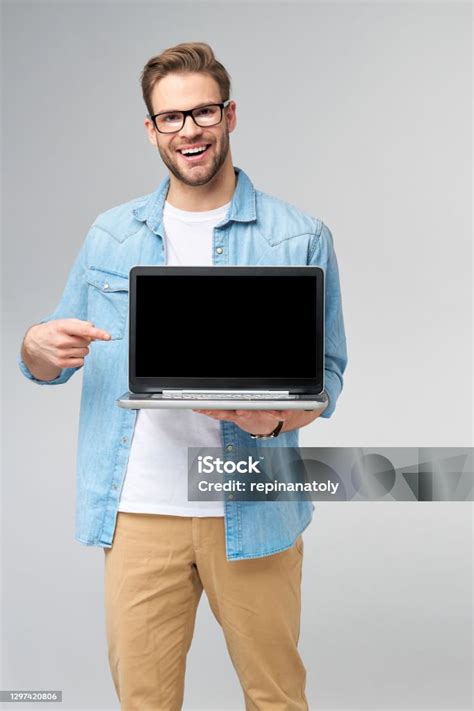 회색 스튜디오 배경 위에 고립 된 노트북을 들고 청바지 셔츠를 입고 안경을 착용 하는 집중된 젊은 수염 남자 25 29세에 대한 스톡 사진 및 기타 이미지 Istock