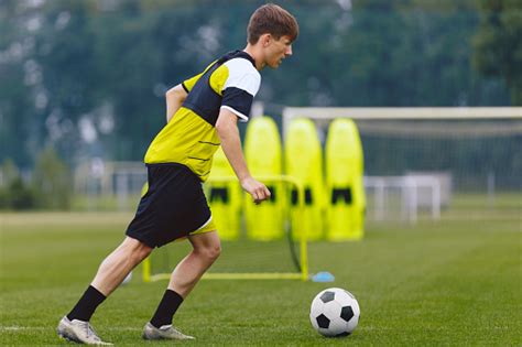 훈련장에서 축구공을 달리는 소년 잔디 밭에서 축구를 연습하는 젊은 선수 축구 벽 마네킹 세트 및 훈련 목표 배경 마네킹에 대한