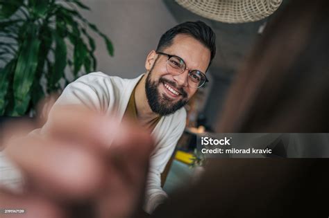 사진은 남자를 중심으로하는 테이블에서의 진심 어린 순간을 포착합니다 그는 날카롭게 세밀하고 표정은 따뜻하고 참여적이며 마치 사려 깊은 이야기를 나누거나 열심히 듣는 것