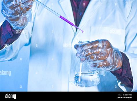 Scientist Pouring Color Liquid Into A Conical Flask With A Dropper