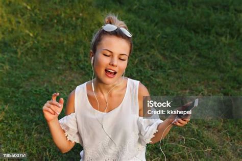 헤드폰과 기호와 전화에 음악을 듣고 행복한 소녀 스마트 폰용 앱의 오디오 젊은 여성이 춤을 추고 손에 스마트 폰으로 야외에서 즐거운 시간을 보세요 Mp3 플레이어에 대한