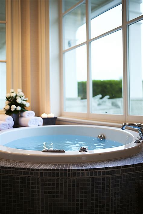 A Large Jacuzzi Tub Sitting Next To Two Windows Background Wallpaper