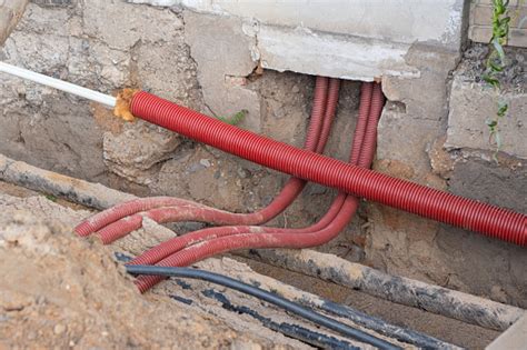 빨간색 골판지 파이프의 전기 케이블은 거리의 지하에 묻혀 있습니다 전기 케이블 인프라 설치의 허브 많은 에너지를 가진 건설 현장