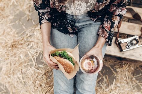 맛있는 햄버거와 레모네이드 상위 뷰 육즙이 많은 햄버거를 들고 상쾌한 칵테일을 들고 있는 세련된 힙스터 여성 길거리 음식 축제에서 보헤미안 소녀 여름철 사진