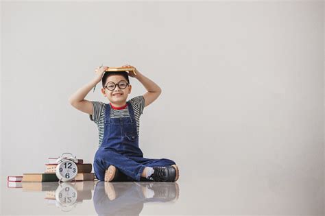 학교 및 교육 개념으로 돌아가기 쾌활한 소년은 손을 들고 책을 하얀 배경에 머리에 올려 놓고 있다 가방에 대한 스톡 사진 및