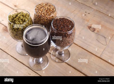 Glasses Filled With Dark Beer Different Malts And Hops Over A Wooden