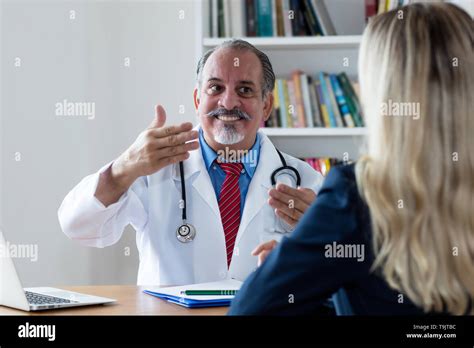 Laughing Doctor Explaining Medical Treatment To Female Patient At