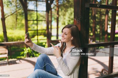 가벼운 캐주얼 옷을 입고 아름 다운 여자의 초상화입니다 여성 봄 자연에 야외 거리에 도시 공원에 앉아 웃 고 휴대 전화 또는