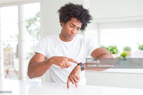 캐주얼 한 흰색 티셔츠를 입고 젊은 아프리카 계 미국인 남자 손목 시계에 시간을 확인 편안 하 고 자신감 T 셔츠에 대한 스톡