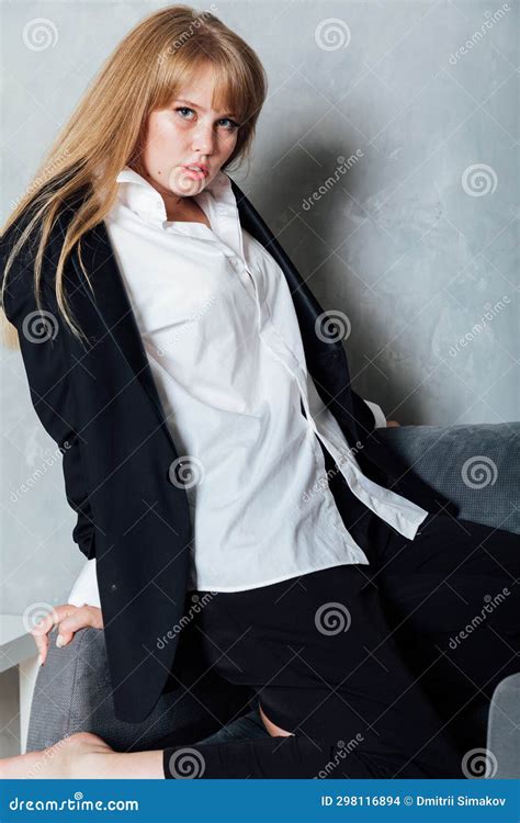 Beautiful Young Fashionable Woman In Black Business Suit Sitting On A