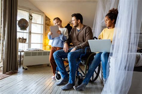 Happy Father In Wheelchair With Interracial Daughters Using Laptop