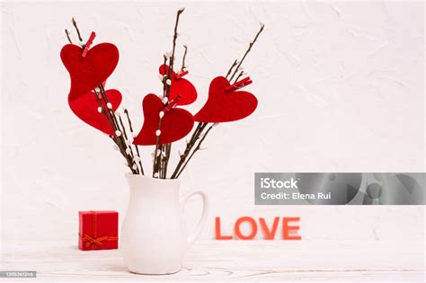 발렌타인 데이 테이블에 흰색 용기에 버드 나무 가지에 펠트로 만든 빨간 마음 선물과 흰색 배경에 단어 사랑 0명에 대한 스톡
