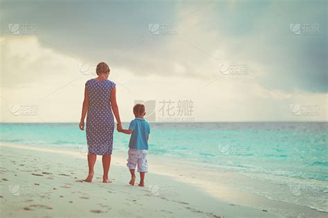 母亲和小儿子在日落海滩上散步