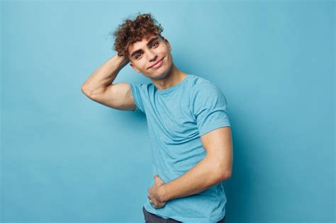 Premium Photo Curly Man In A Tshirt On A Colored Background Posing