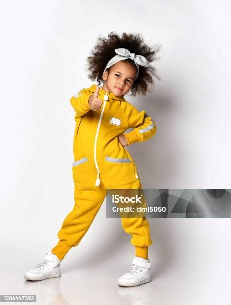 따뜻한 노란색 점프수트와 운동화를 입은 자신감 넘치는 귀여운 뮬라토 다크 스킨 아이 소녀 낙하복에 대한 스톡 사진 및 기타 이미지 낙하복 아이 4 5세 Istock